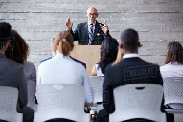 Senior businessman addressing delegates at conference - Stock Photo ...
