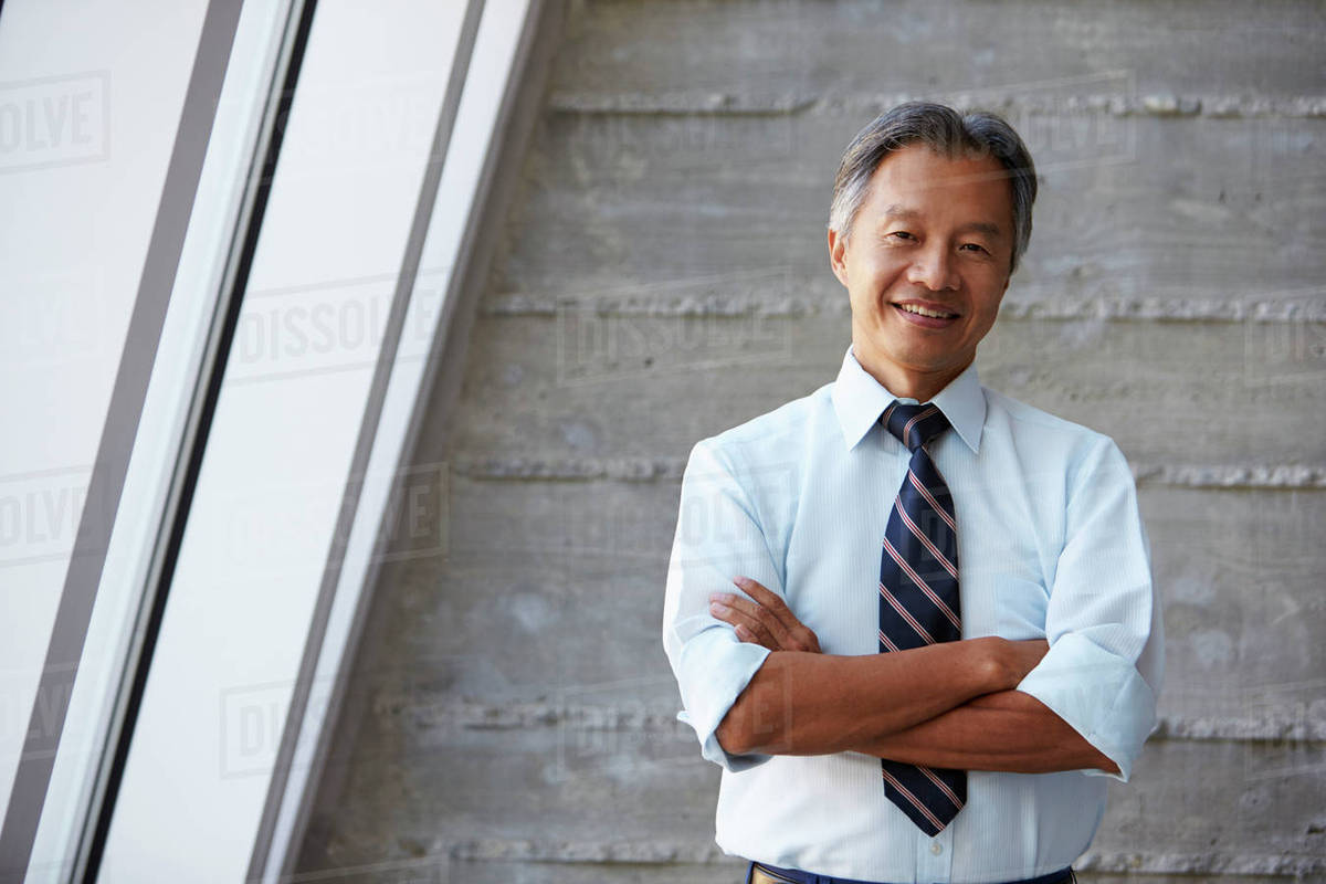 Businessman standing against wall in modern office - Royalty-free Stock ...