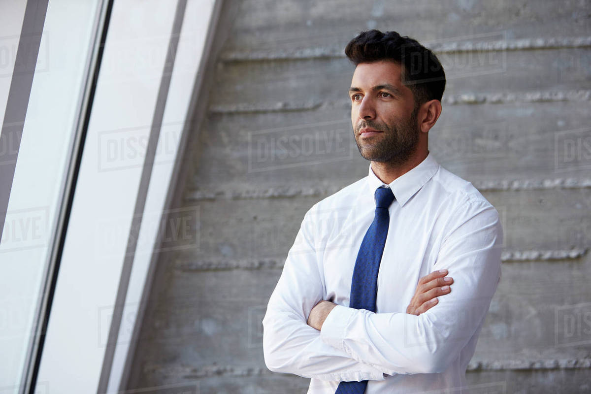 Businessman standing against wall in modern office - Royalty-free Stock ...