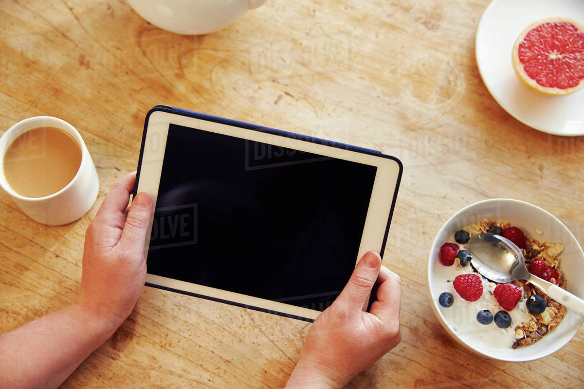 Person looking at digital tablet whilst eating breakfast - Royalty-free ...