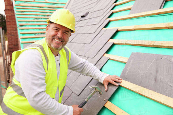Construction worker on building site laying slate tiles - Royalty-free ...