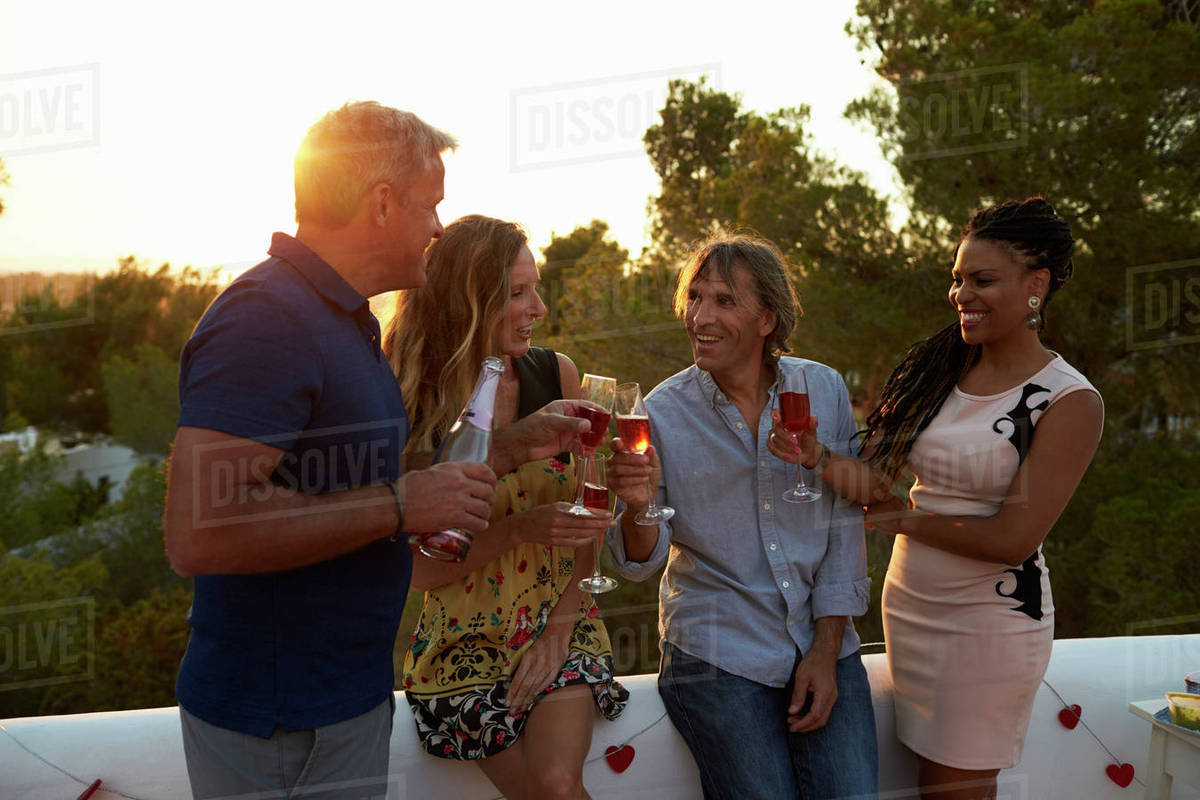 Two couples enjoying drinks on a rooftop at sunset, Ibiza - Royalty ...