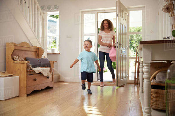 Excited boy returning home from school with mother - Stock Photo - Dissolve