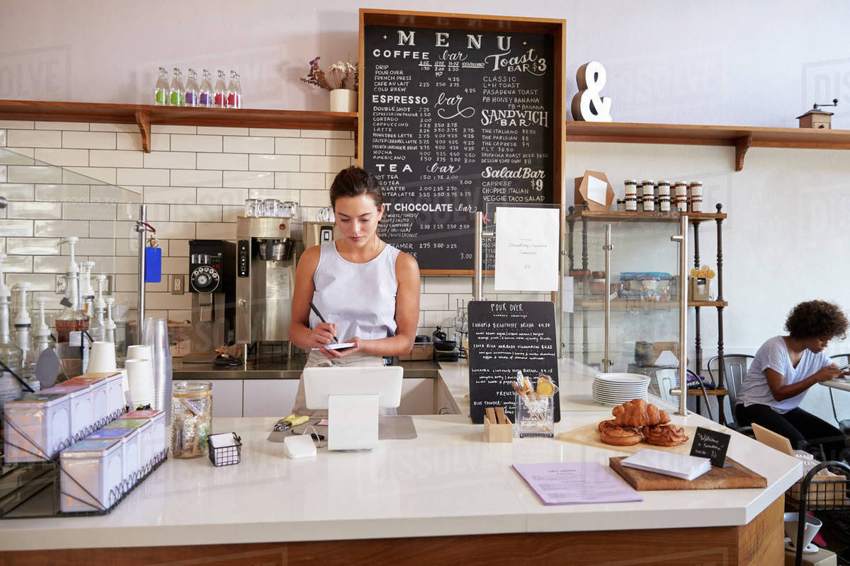 Waitress writing customer’s order at counter of coffee shop - Royalty ...