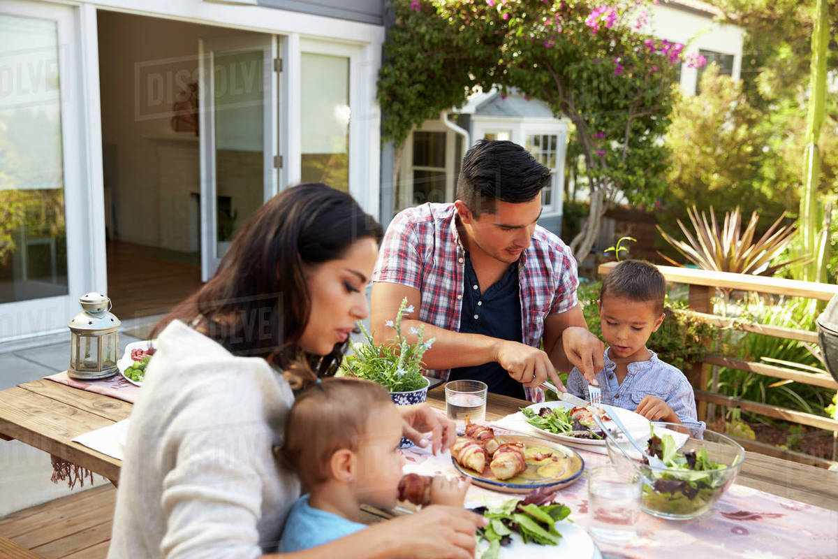 Family at home eating outdoor meal in garden together - Stock Photo ...