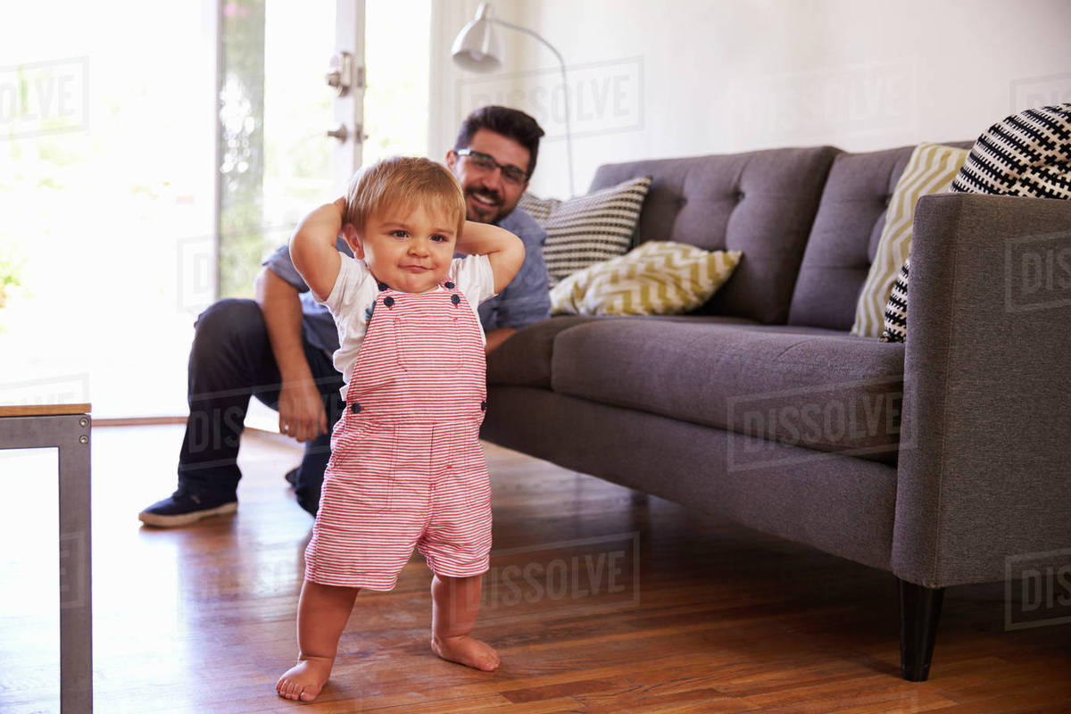 Father watching baby daughter take first steps at home - Royalty-free ...