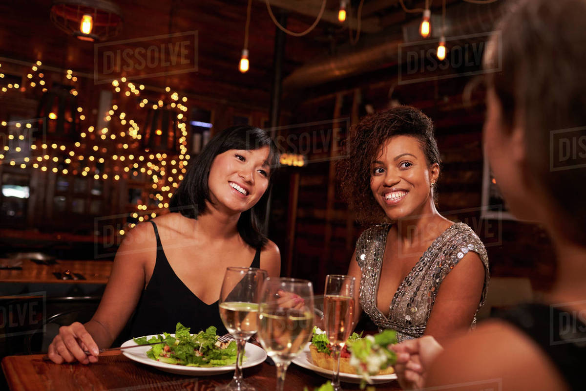 Three female friends enjoying dinner at a restaurant - Stock Photo ...