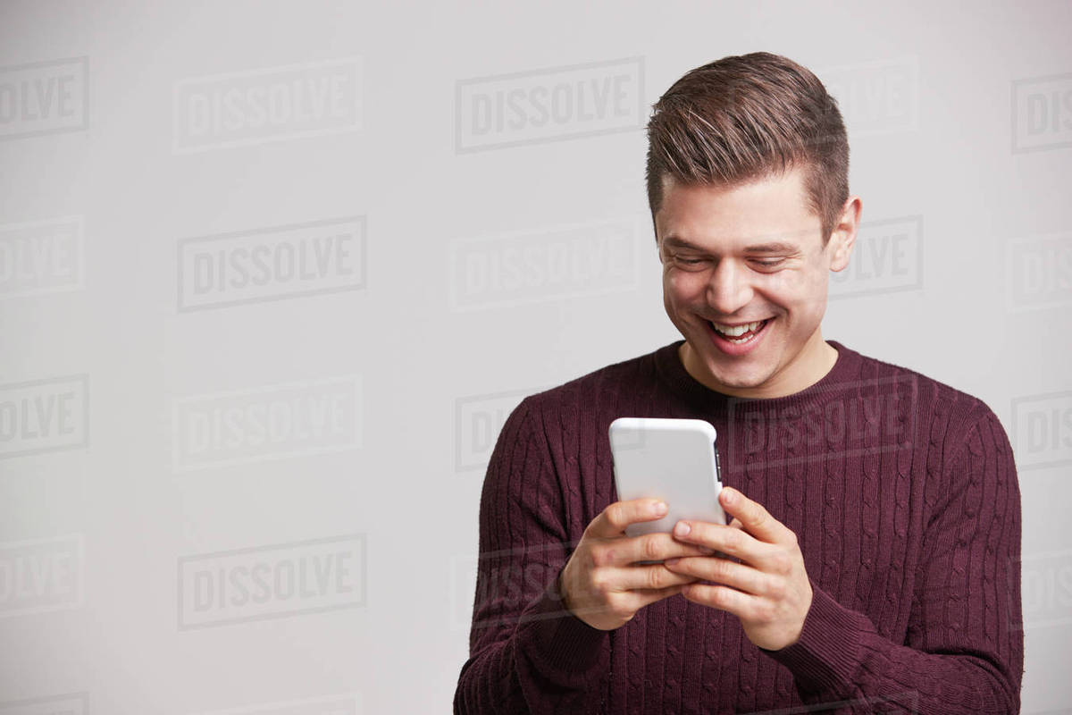 Portrait of a laughing young white man using a smartphone - Stock Photo ...