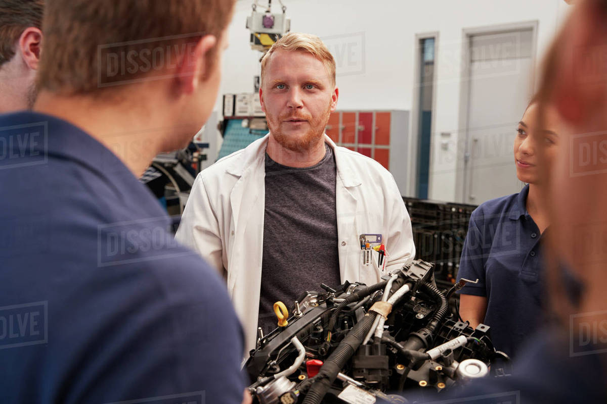 Car mechanic listening to questions from apprentices - Royalty-free ...