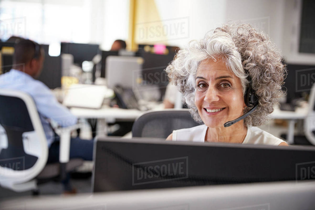 Middle aged woman working at computer with headset in office - Royalty ...