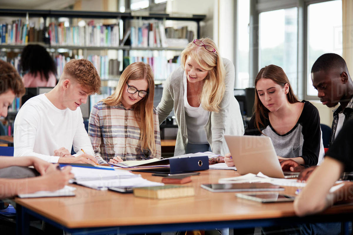 Female Teacher Working With College Students In Library - Royalty-free ...