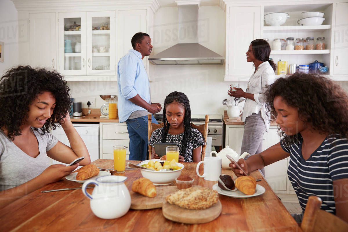 Family With Teenage Children Eating Breakfast In Kitchen - Royalty-free ...