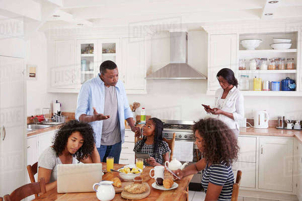 Family Sitting Around Breakfast Table Using Digital Devices - Royalty ...