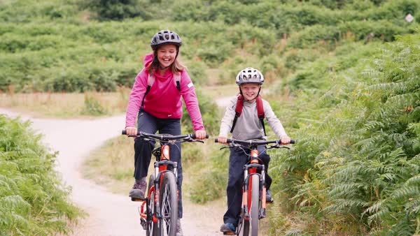 Two children having fun on mountain bikes in the countryside ride past ...