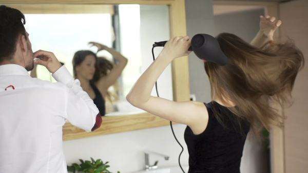 Couple in bathroom, woman drying hair and man brushing teeth - Stock ...