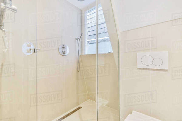 Modern shower cabin with glass walls and chrome faucet in mansard ...