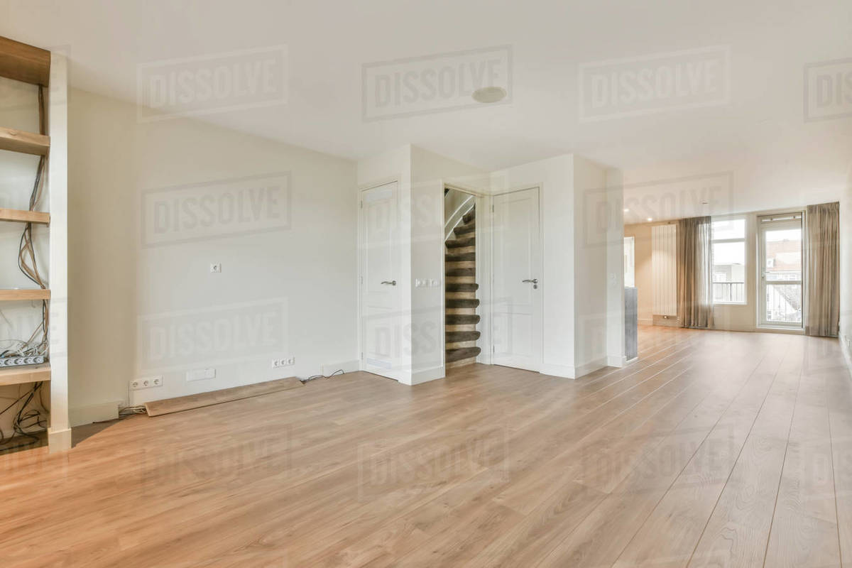 Large room with dark parquet floor and adjoining staircase - Stock ...