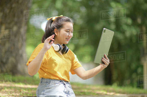 Asian girls greet friends with a tablet, wearing a yellow shirt and ...