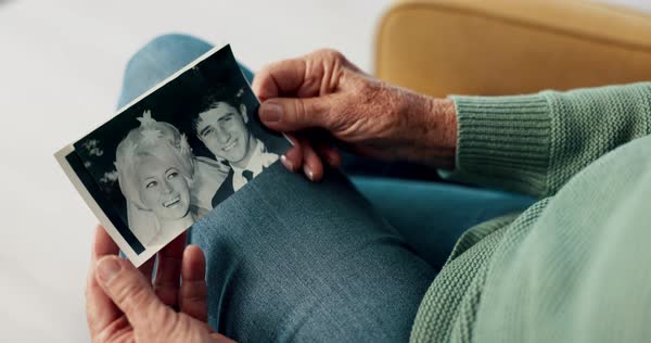 Hands, photograph and memory on a home sofa for nostalgia, history and ...