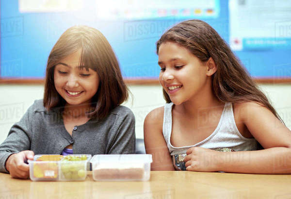 Happy girls, students and lunchbox of food in classroom at school for ...