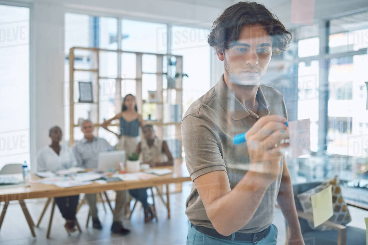 Businessman writing, planning and brainstorming on board in a ...