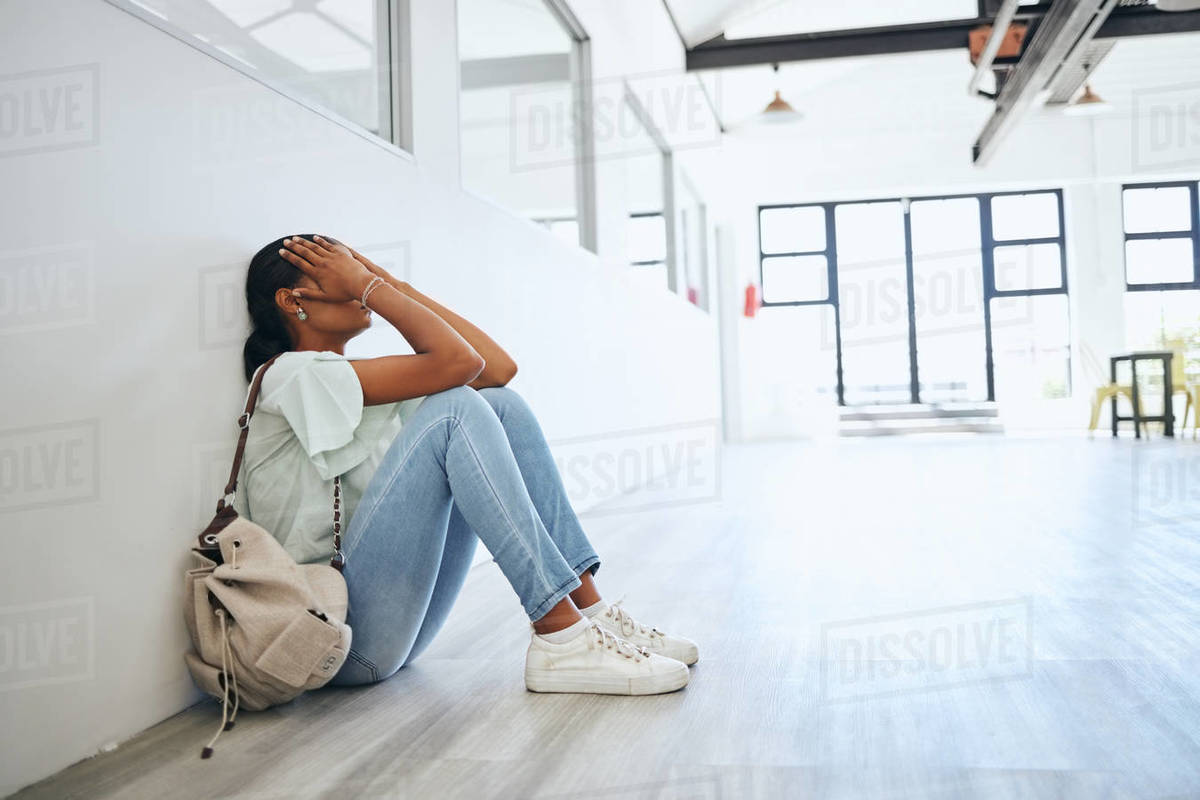 Sad, depression and anxiety student woman on floor in university campus ...