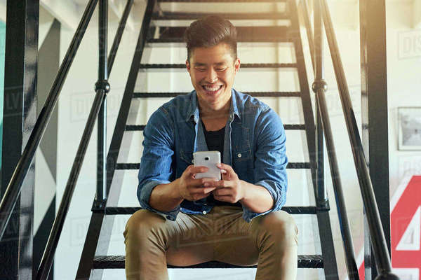 Asian man, texting and office stairs with phone, smile and ...