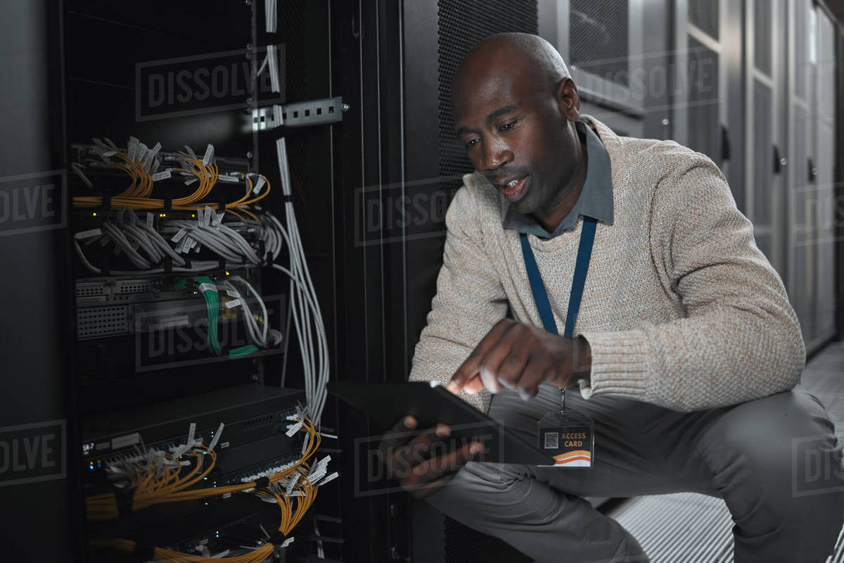 Data center or black man on tablet in server room on database maintenance or software update ...