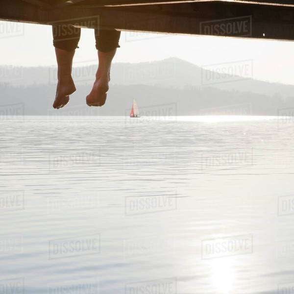 Man dangling his legs from a pier - Royalty-free Stock Photo | Dissolve