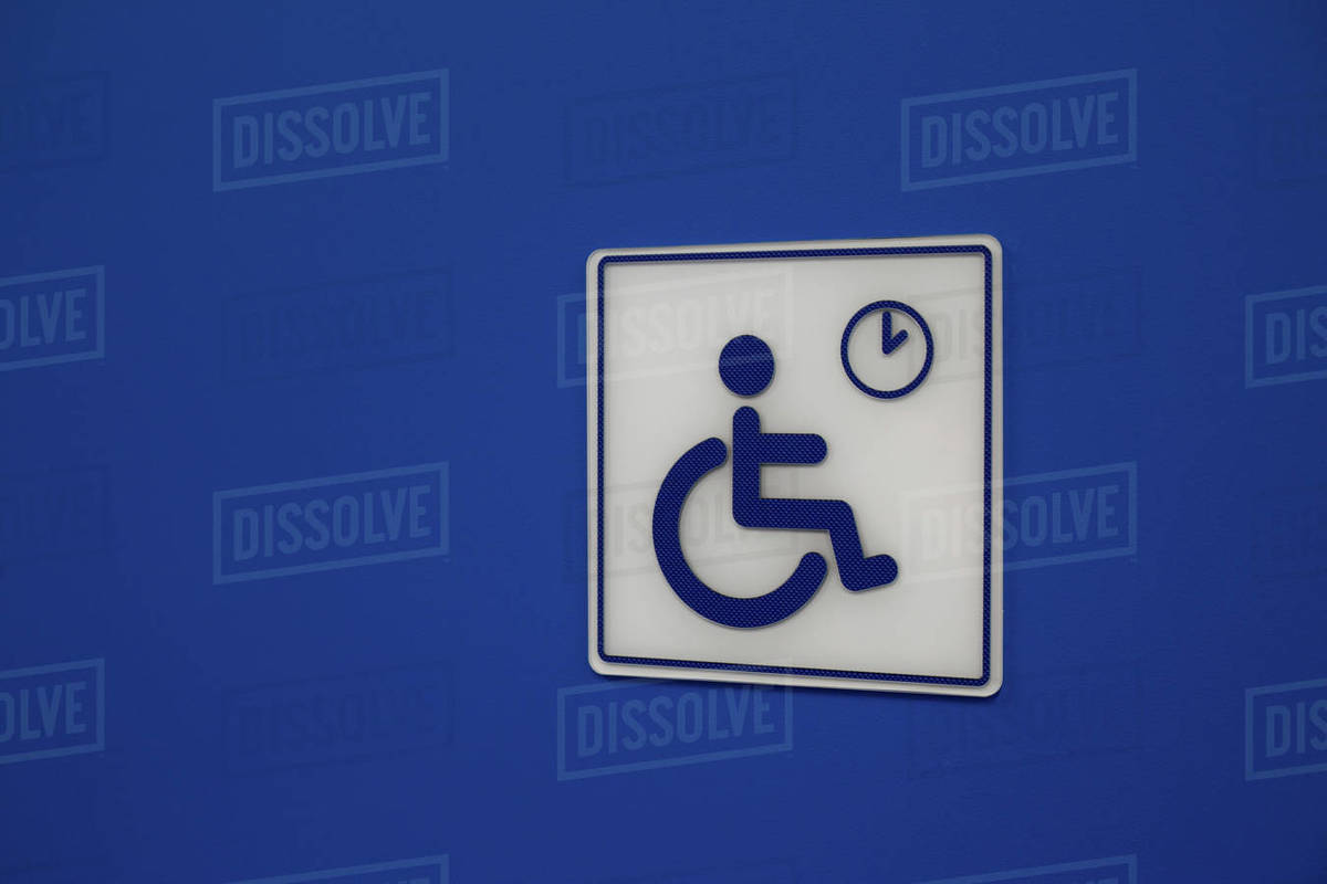 White square sign with a blue wheelchair and a clock in the corner on ...