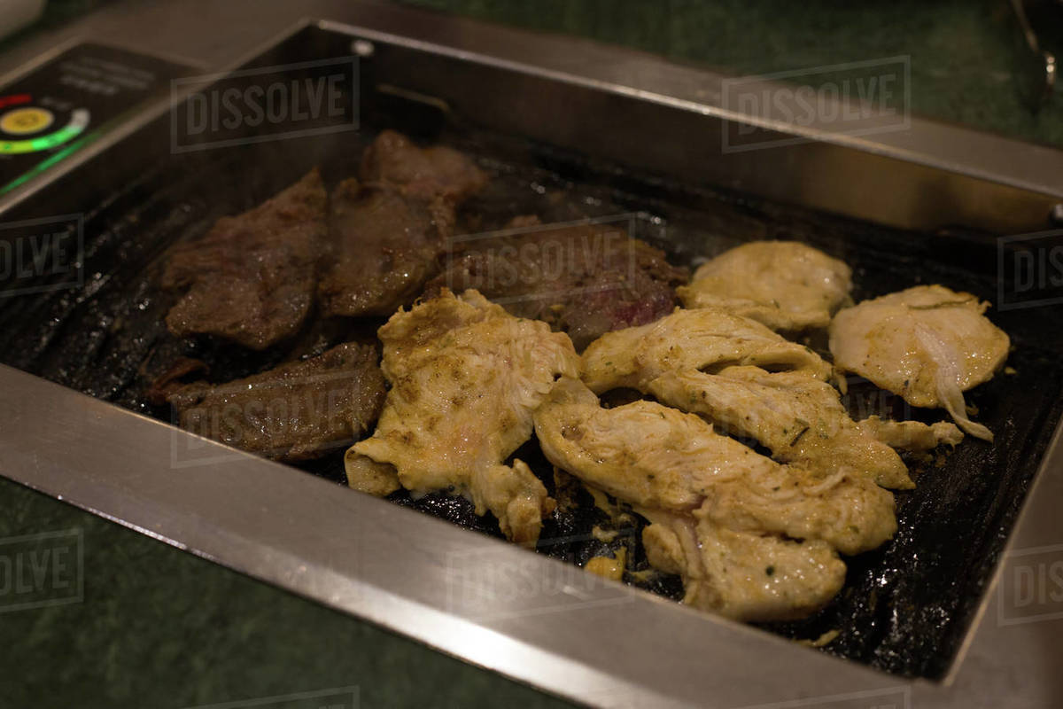Beef and chicken meats are grilled at the restaurant table. Self ...