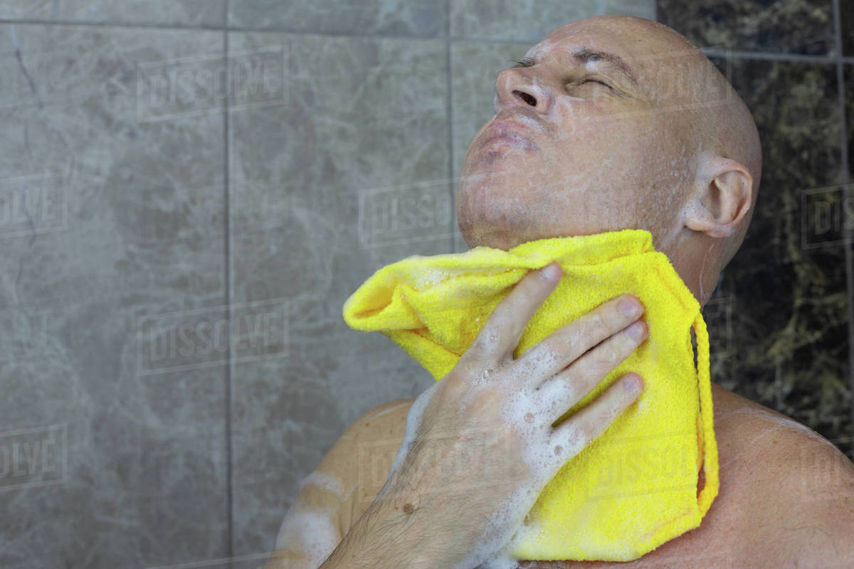 Bald man in shower washing his head with washcloth and foam, body ...