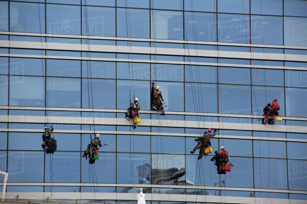 Climbers clean the glass facade of skyscraper, hard work at height ...