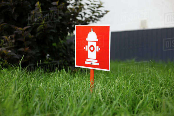 Red square plate with a white sign of a hydrant on a lawn in the grass ...