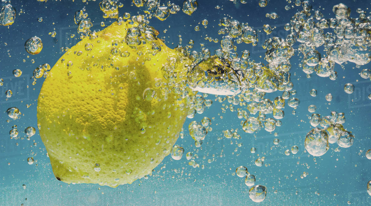 Underwater lemon slice in soda water or lemonade with bubbles. Refreshing soda tonic fizzy ...