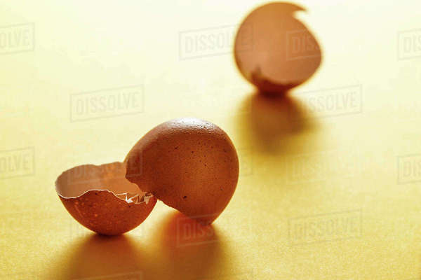 Egg shells on yellow surface with more shells in the background. View ...