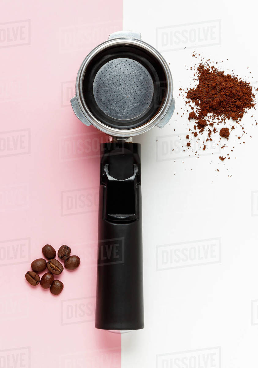 Espresso machine filter holder, ground coffee and coffee beans on pink ...