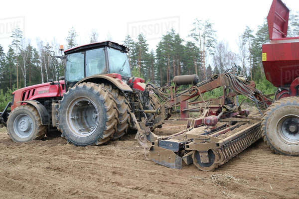 A powerful red diesel tractor with a connected sowing unit, a combine ...