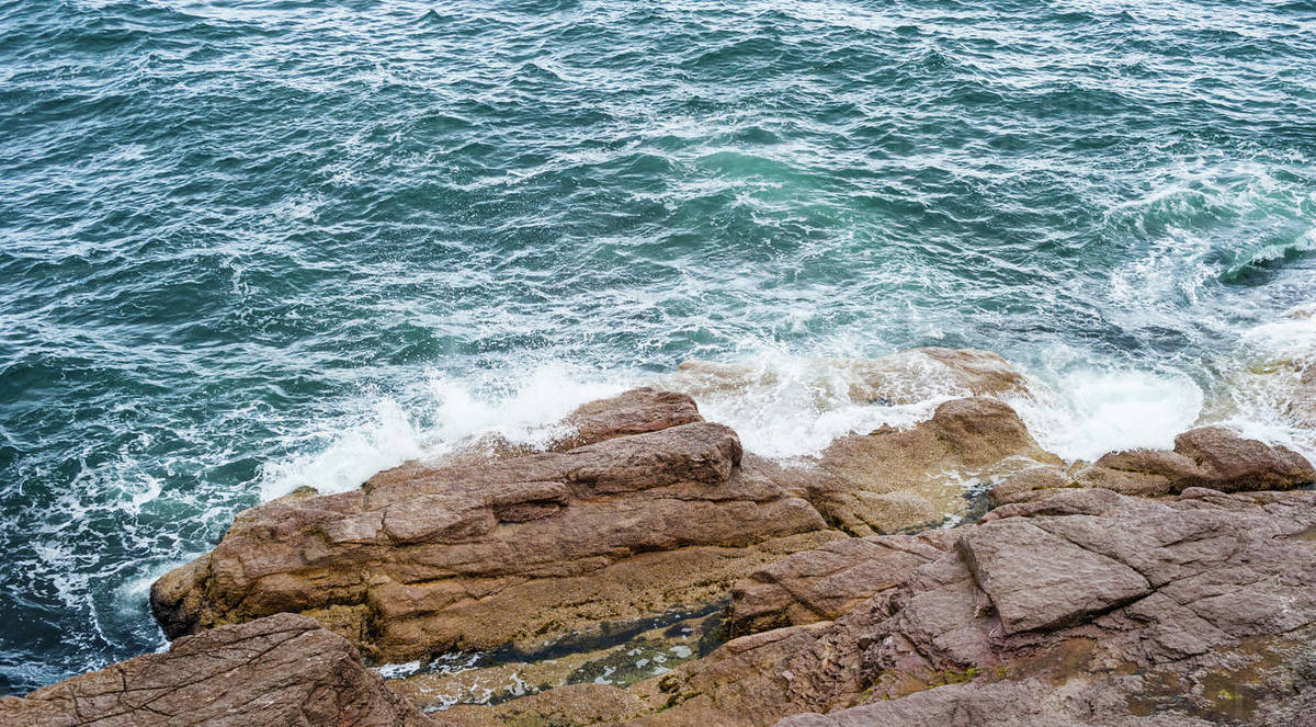 Splashing ocean waves and spray crashing against bare rocks, in ...