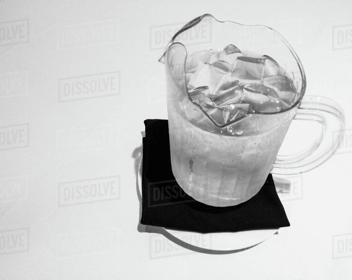 Pitcher with cold water and ice cubes on table napkin. - Royalty-free ...