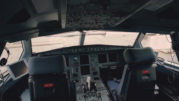 Looking at the interior of an airplane cockpit from behind the pilot ...