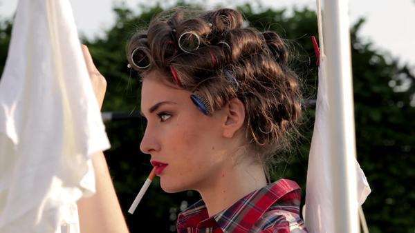Fashion beauty poses in garden wearing hair curlers and cigarette in ...