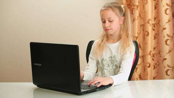 Girl sitting on chair and surfing internet using black laptop computer ...
