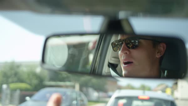 Cool shot of rear view mirror reflection of an angry Caucasian man ...