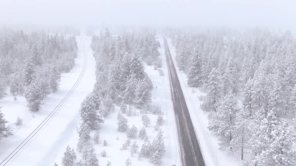 AERIAL: Flying along an empty asphalt road and train tracks leading ...