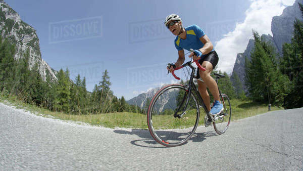 LOW ANGLE: Intense shot of road cyclist pushing himself during ...