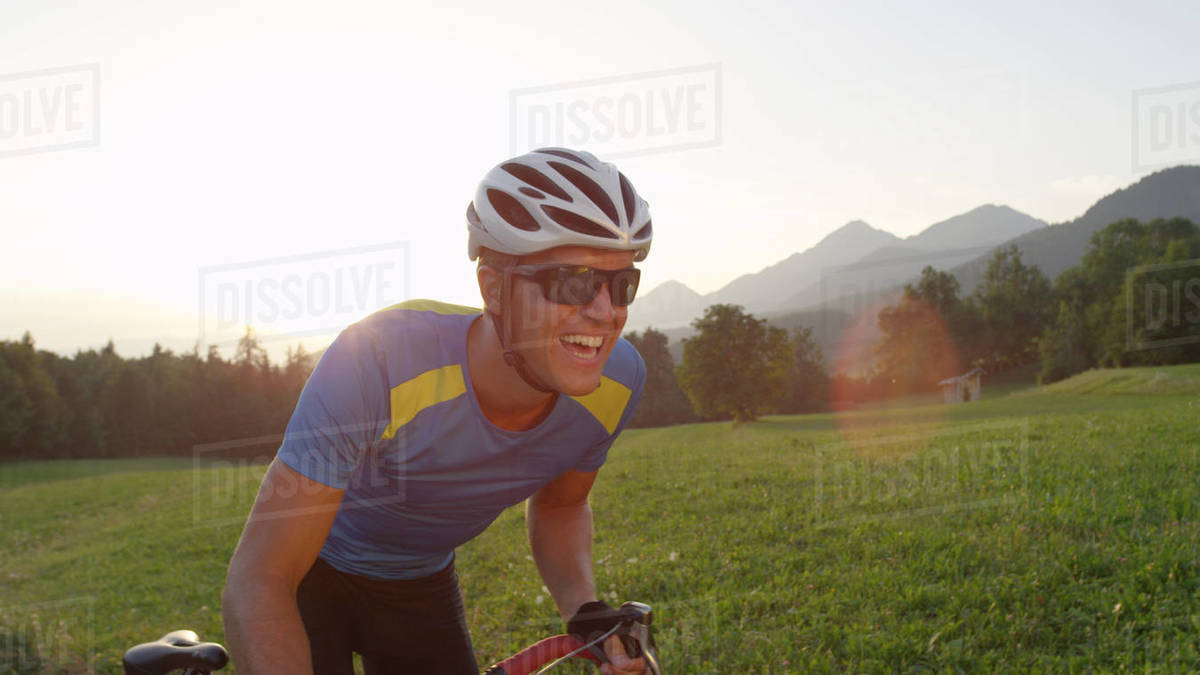 CLOSE UP, LENS FLARE: Exhausted professional male cyclist pushing ...