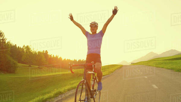 LENS FLARE: Professional biker raising his arms victoriously after ...