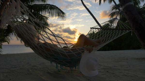 Young woman napping in hammock at beautiful sunrise on the exotic white ...