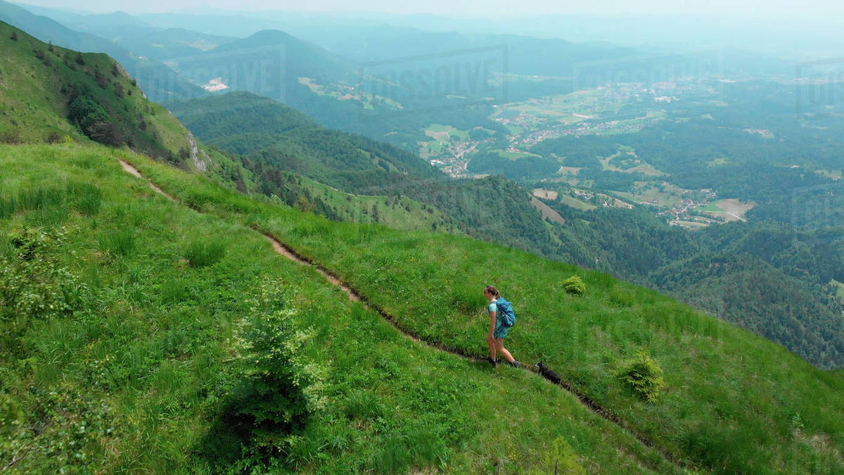 AERIAL: Cute little dog and active female owner hike up a narrow ...